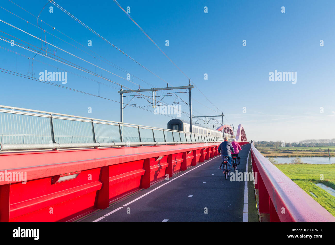 train passing the new red railroad bridge over the IJssel river in the ...