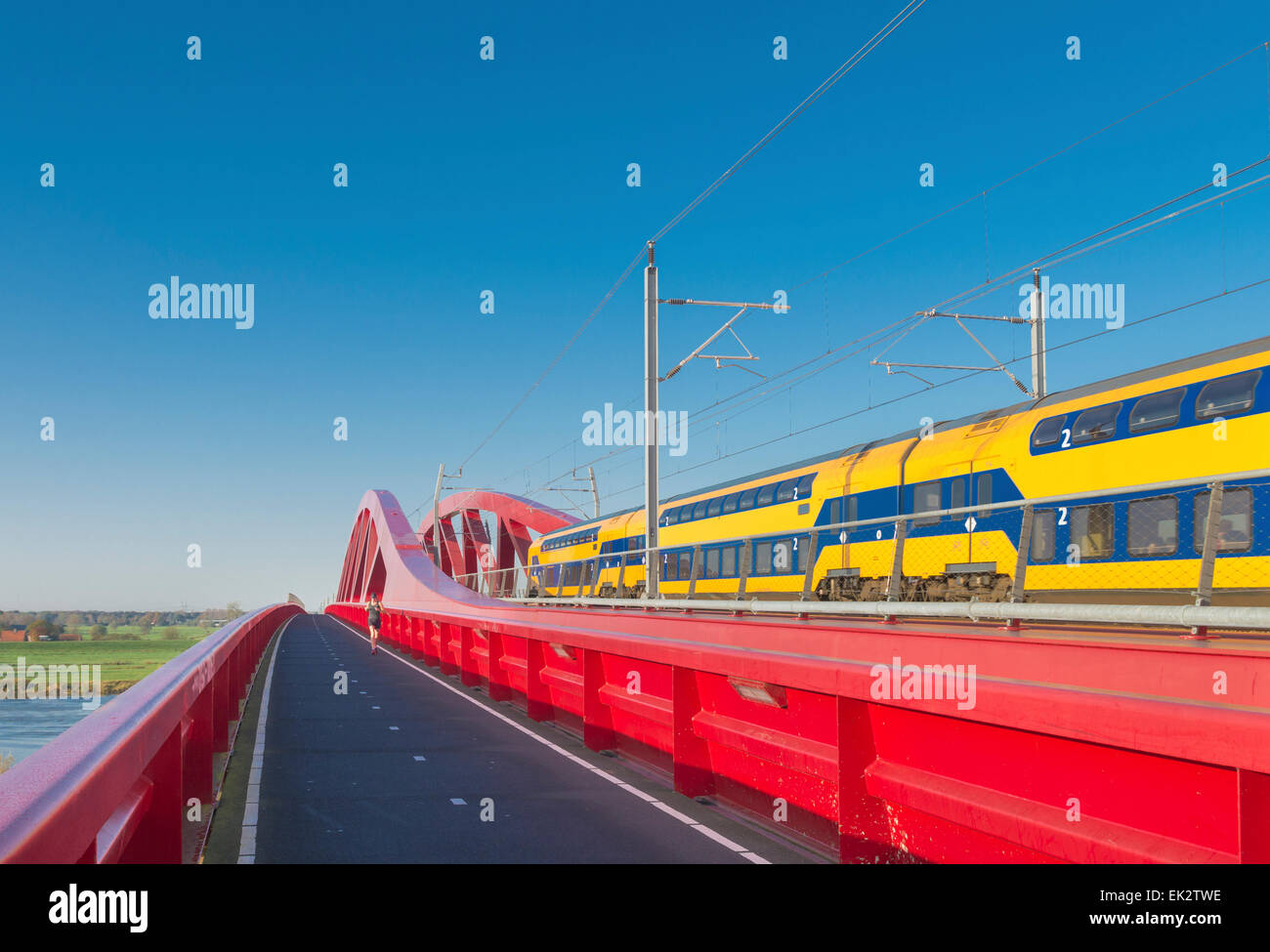 train passing the new red railroad bridge over the IJssel river in the ...