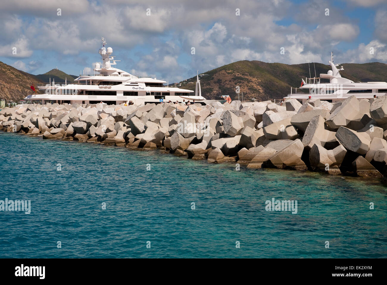 Wall of rocks in St Maarten in the Caribbean with a superyacht behind ...