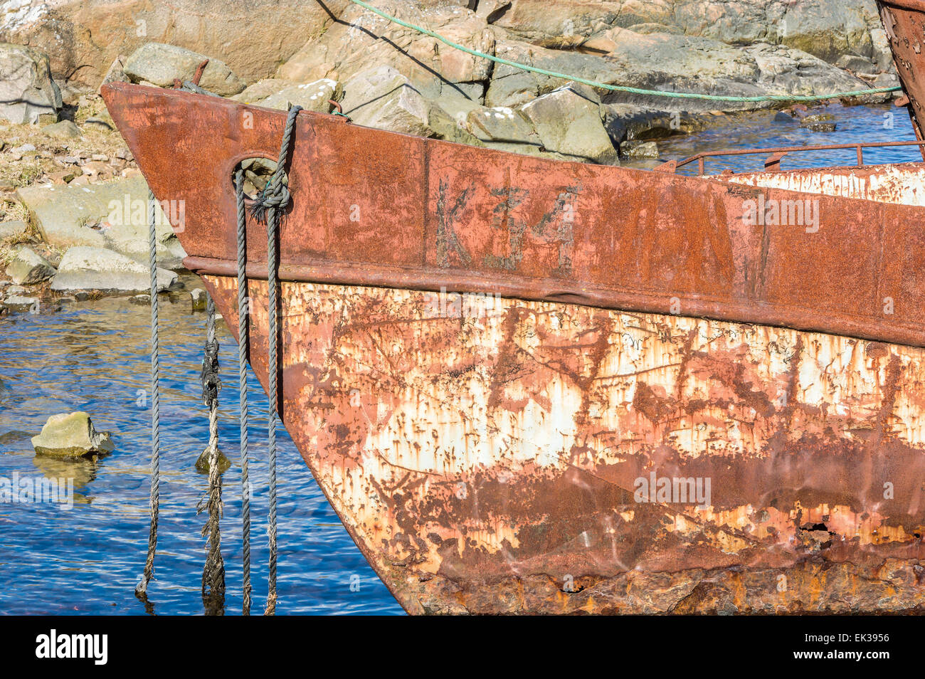 The fore of a rusty old shipwreck with ropes hanging. Still in water ...