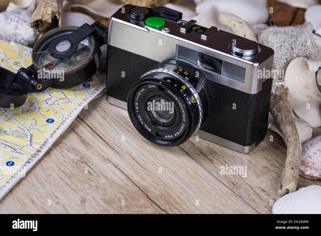 In the picture an analog camera film , a compass and a map, on the ...