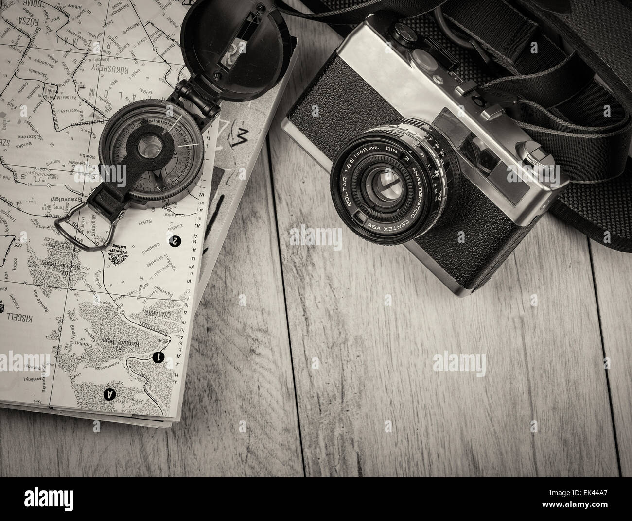 In the picture an analog camera film , a compass,book and a map, on the ...