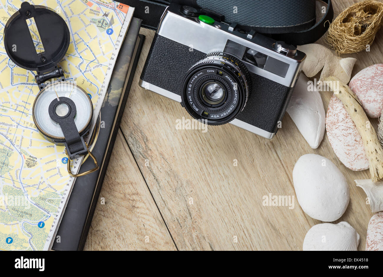 In the picture an analog camera film , a compass,book and a map, on the ...