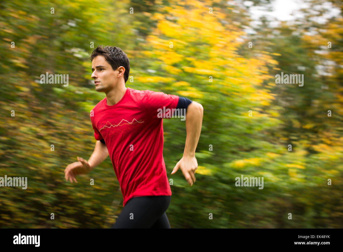 Young man running outdoors in a city park on a fall/autumn day (motion ...