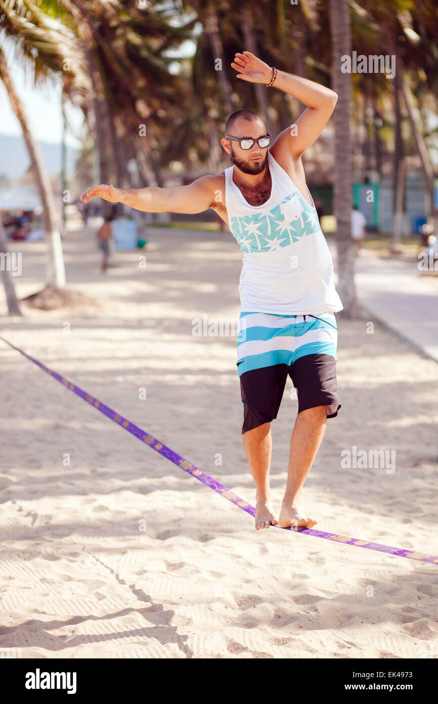 teenage man balancing on slackline on the beach Stock Photo - Alamy