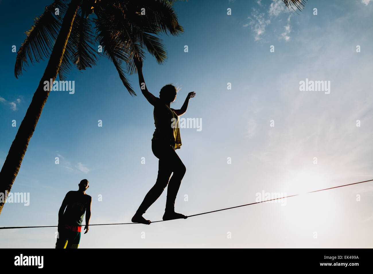 teenage couple balancing on slackline with sky view on the beach ...