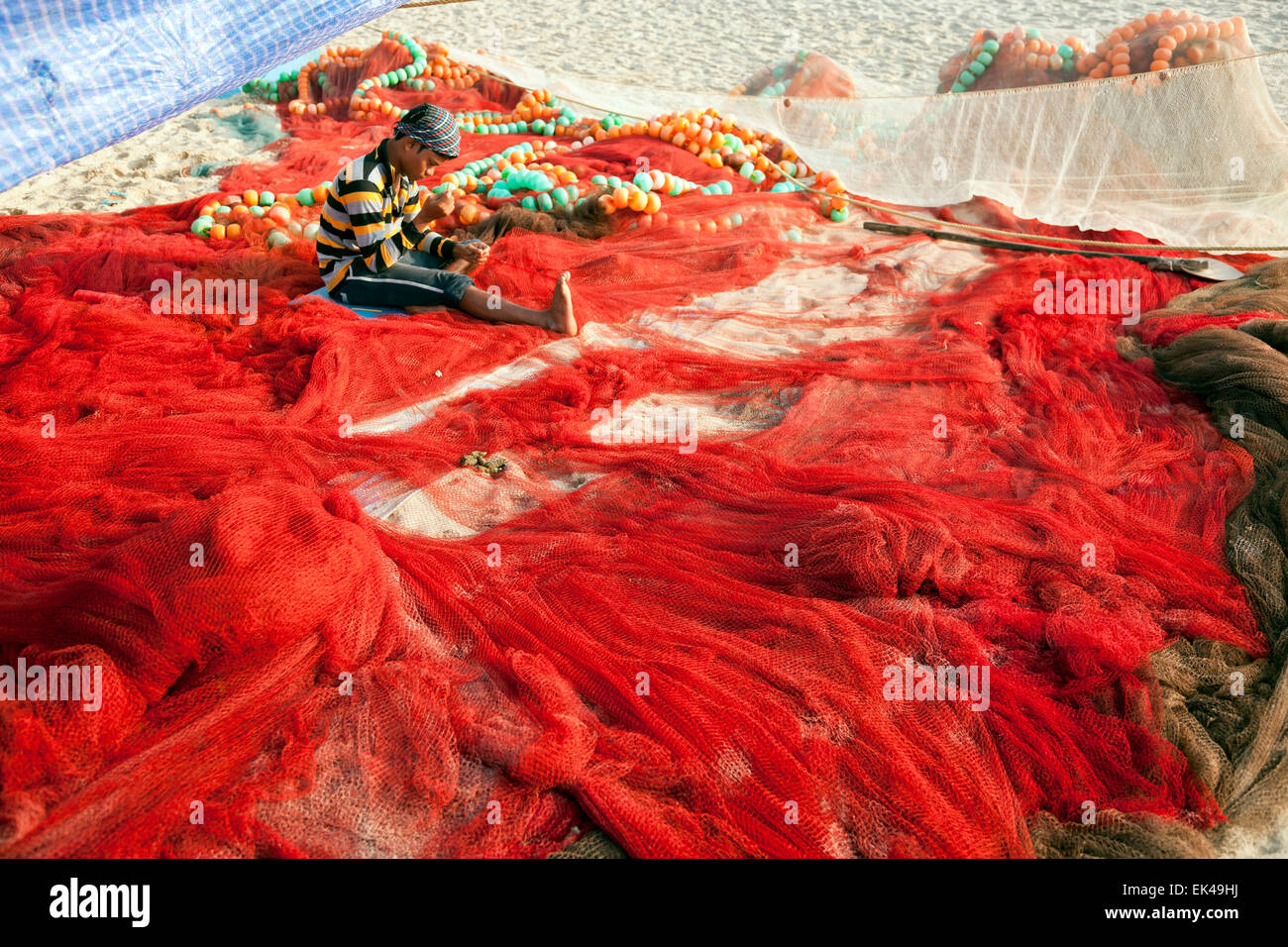 young fisherman repairing his red net on the beach in Benaulim, Goa ...