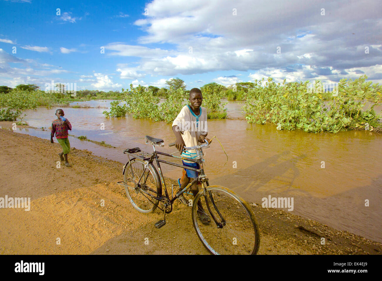 A Kenyan teenager pussing bis bicycle next to the flooding planes in ...