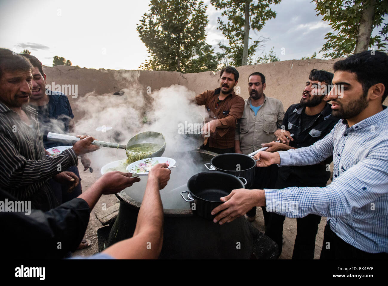 Men serves ritual lunch soup with beans, threads and vegetables for ...