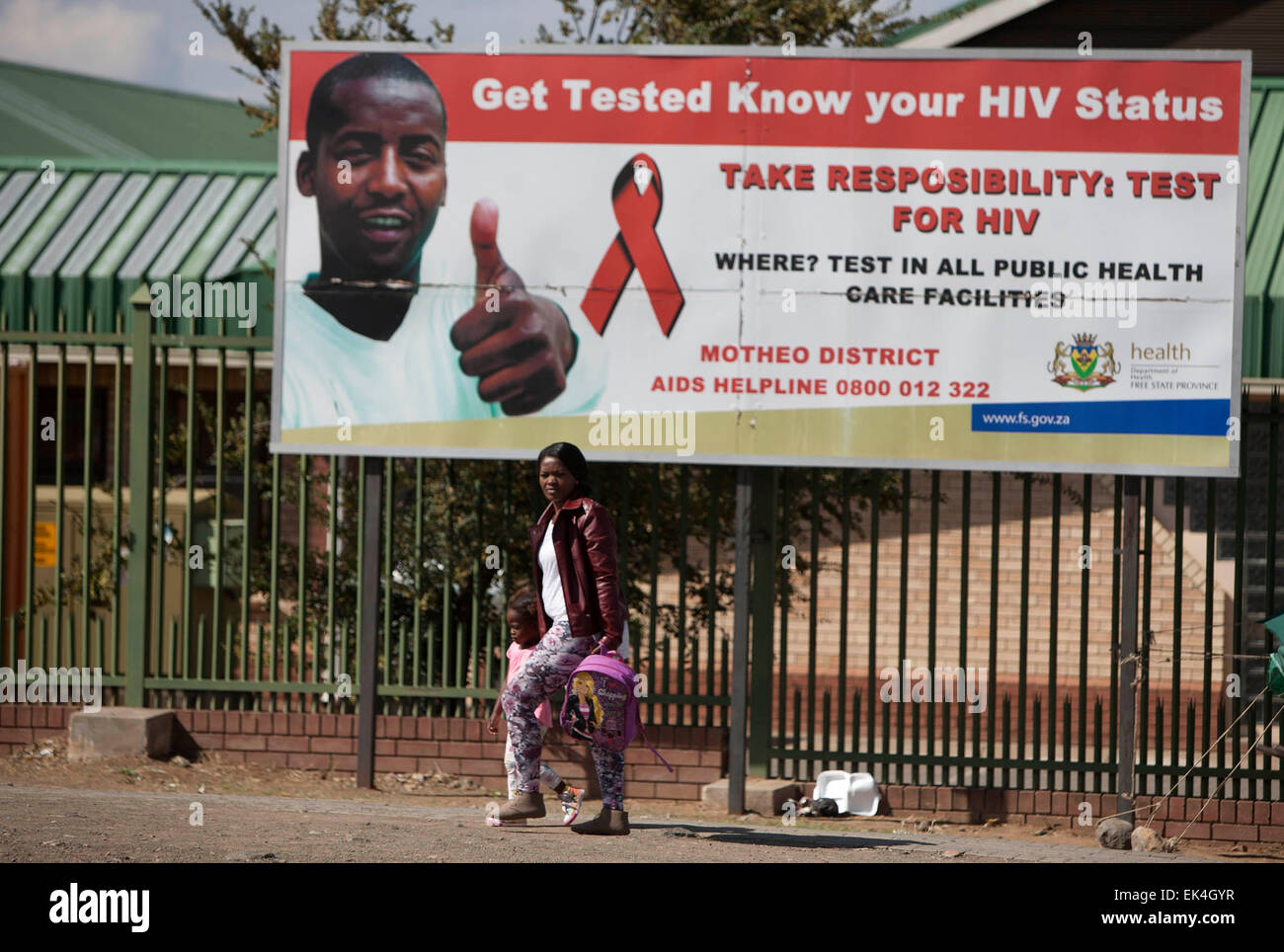 A woman and the kid walking pass the HIV/ AIDS billboard advertising at ...