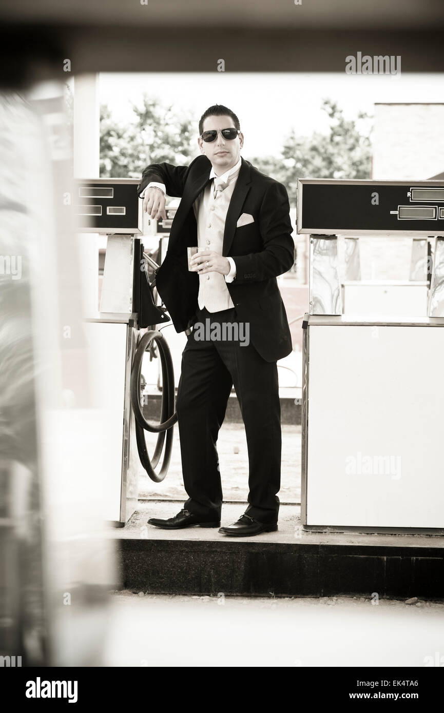 Handsome man in three piece suit at gas station drinking a whiskey ...