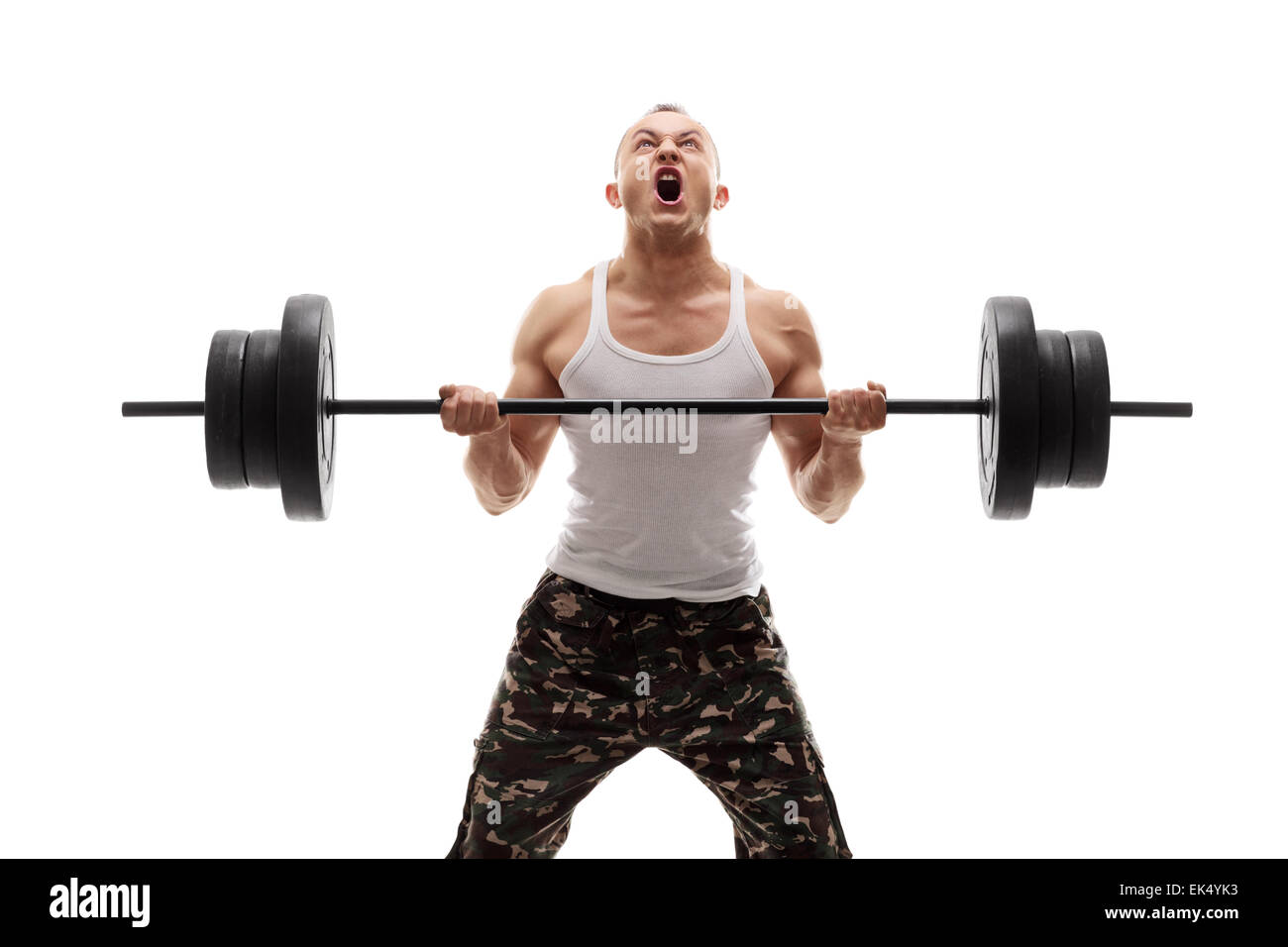 Determined young bodybuilder lifting a heavy barbell and screaming ...