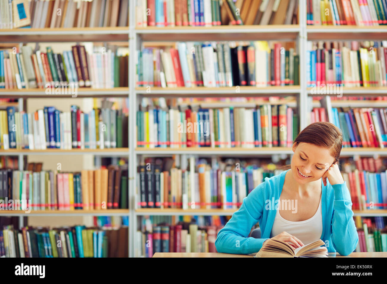 Curious student reading interesting book in library Stock Photo - Alamy