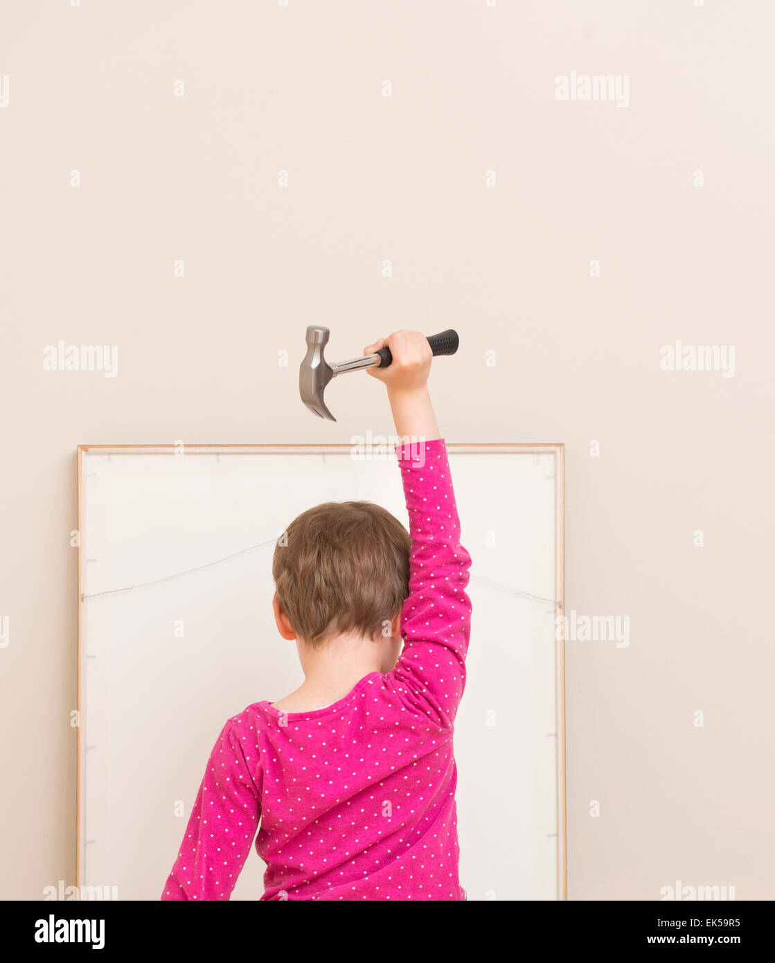 Little girl (5 years) holding hammer over her head and looking at ...