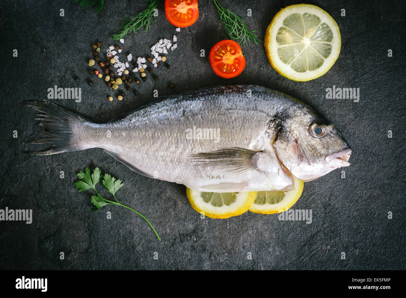 Raw dorada fish with ingredients on dark background Stock Photo - Alamy