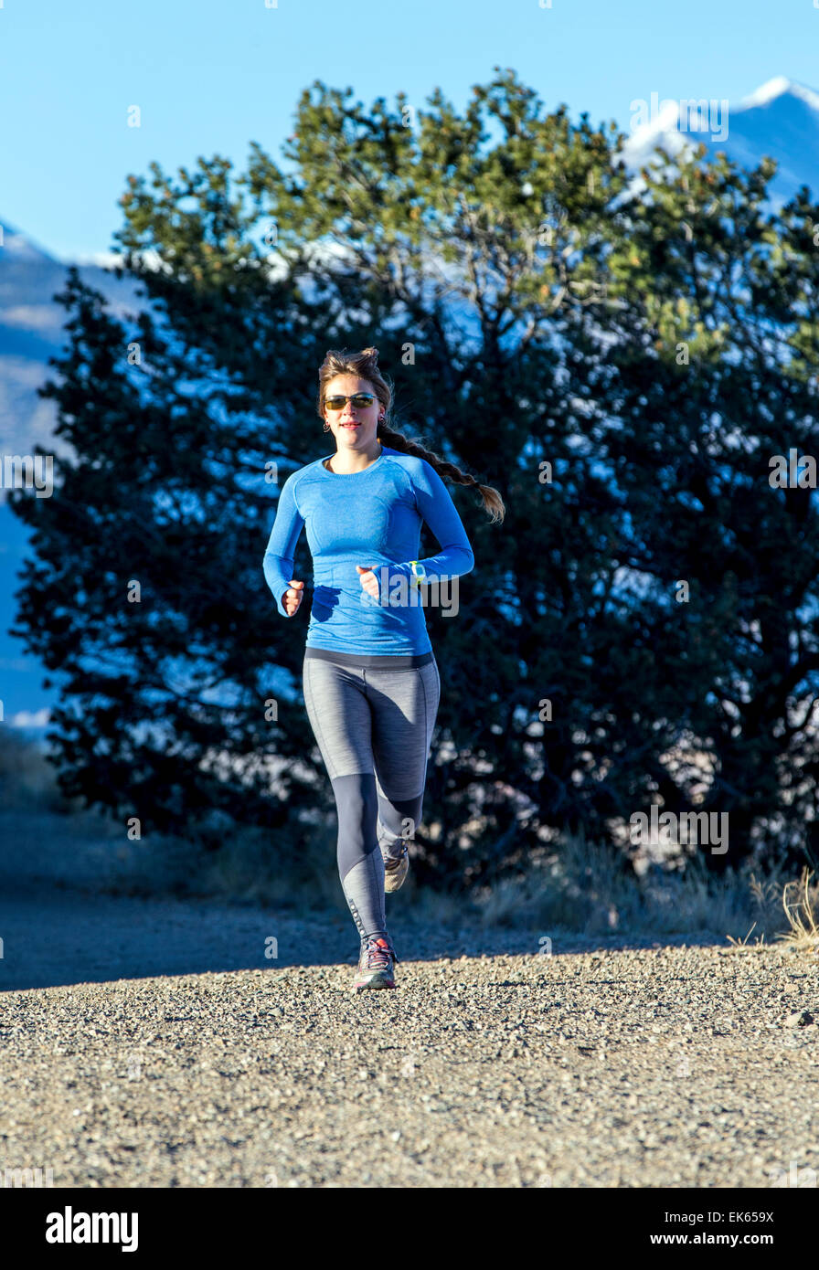 Beautiful young long haired woman running on mountain trails near ...