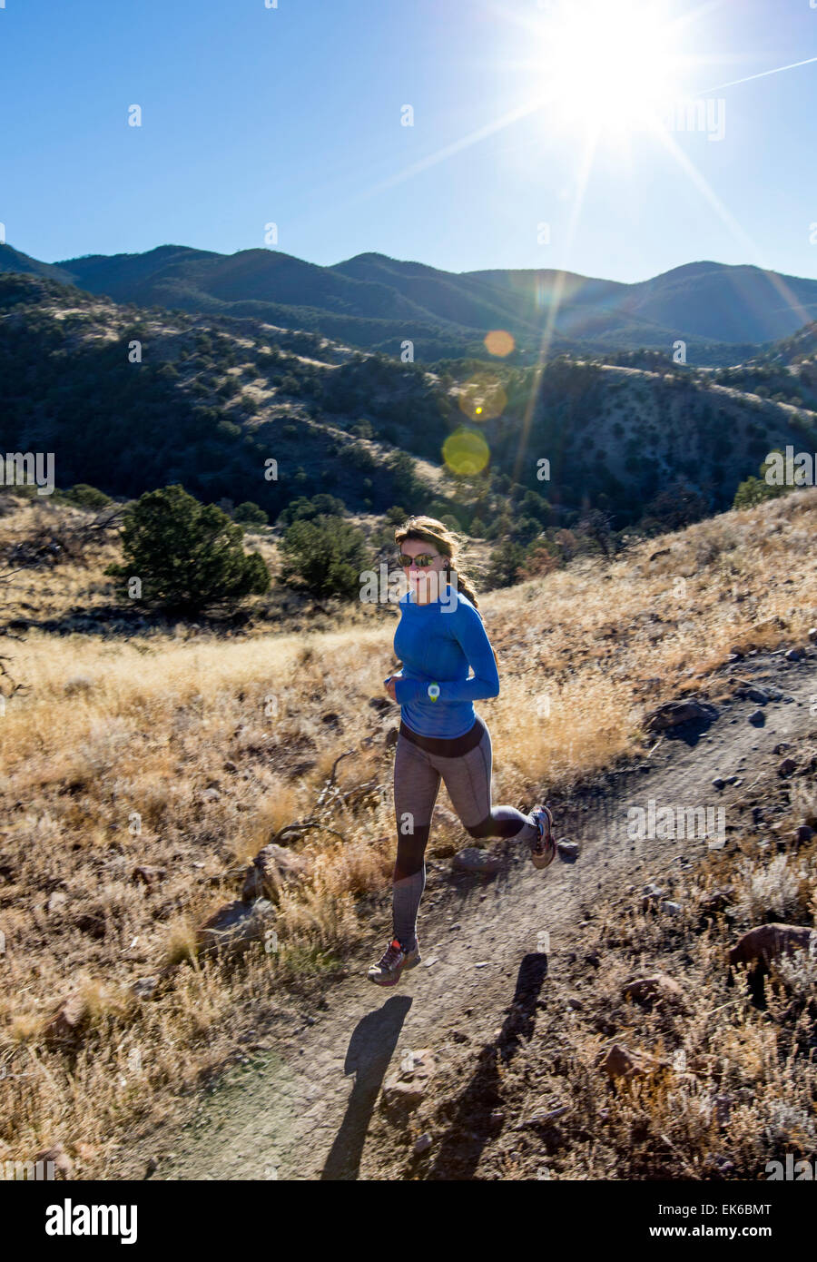 Beautiful young long haired woman running on mountain trails near ...