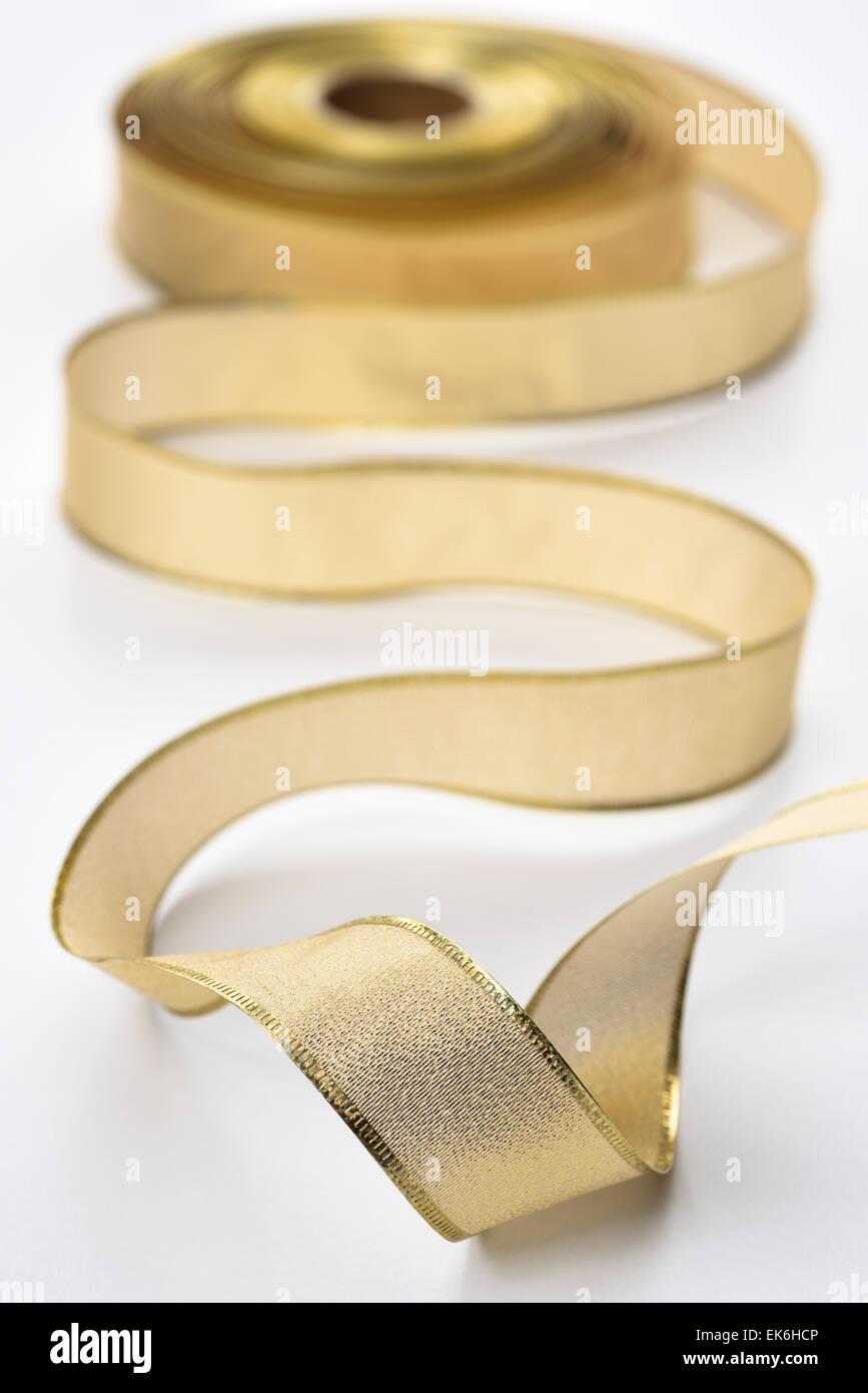 Gold gift wrap ribbon uncoiled from roll on white background Stock ...