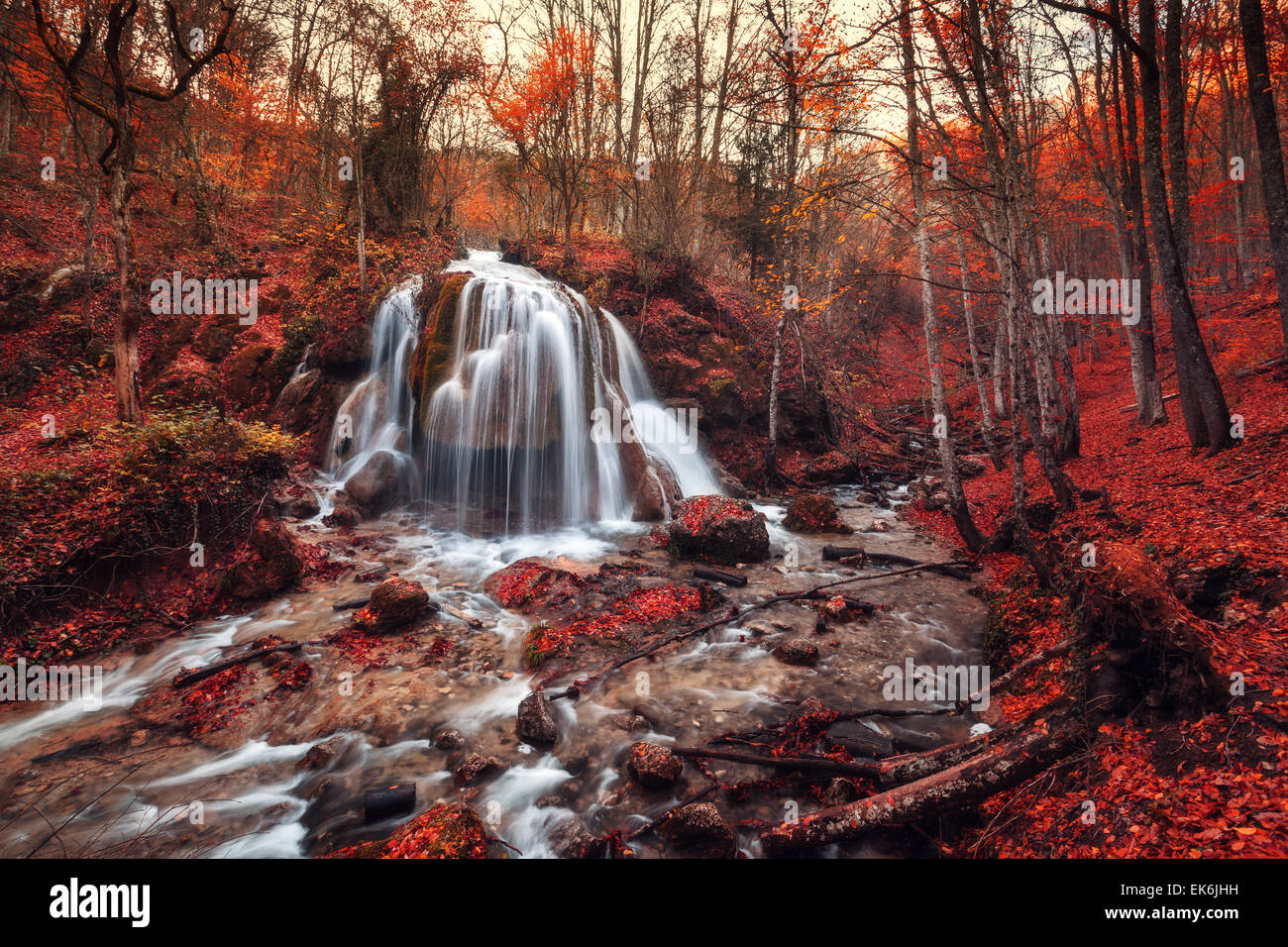 Beautiful waterfall with trees, red leaves, rocks and stones in autumn forest. Silver Stream ...