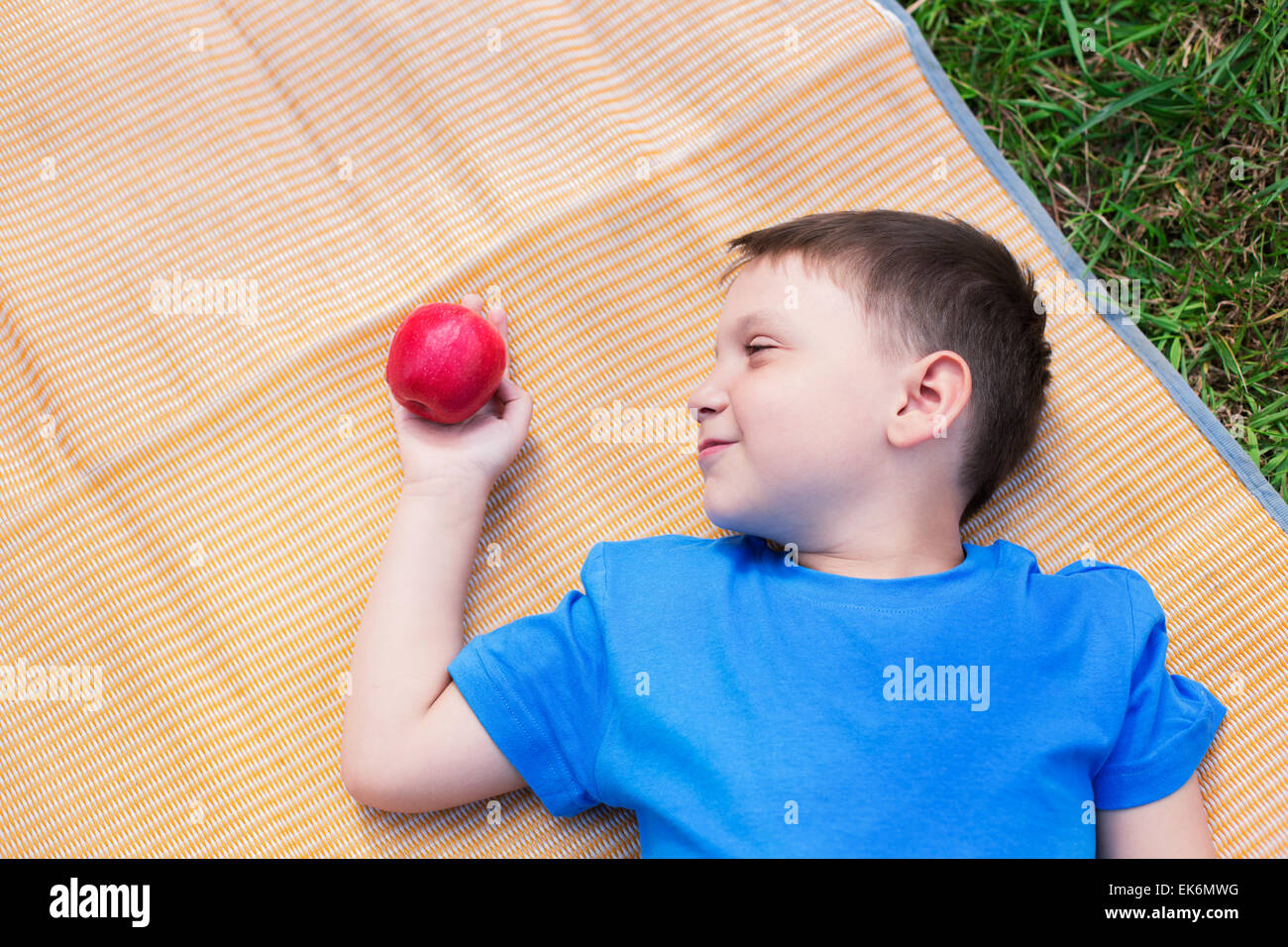 Boy laying on mat and look at red apple Stock Photo - Alamy