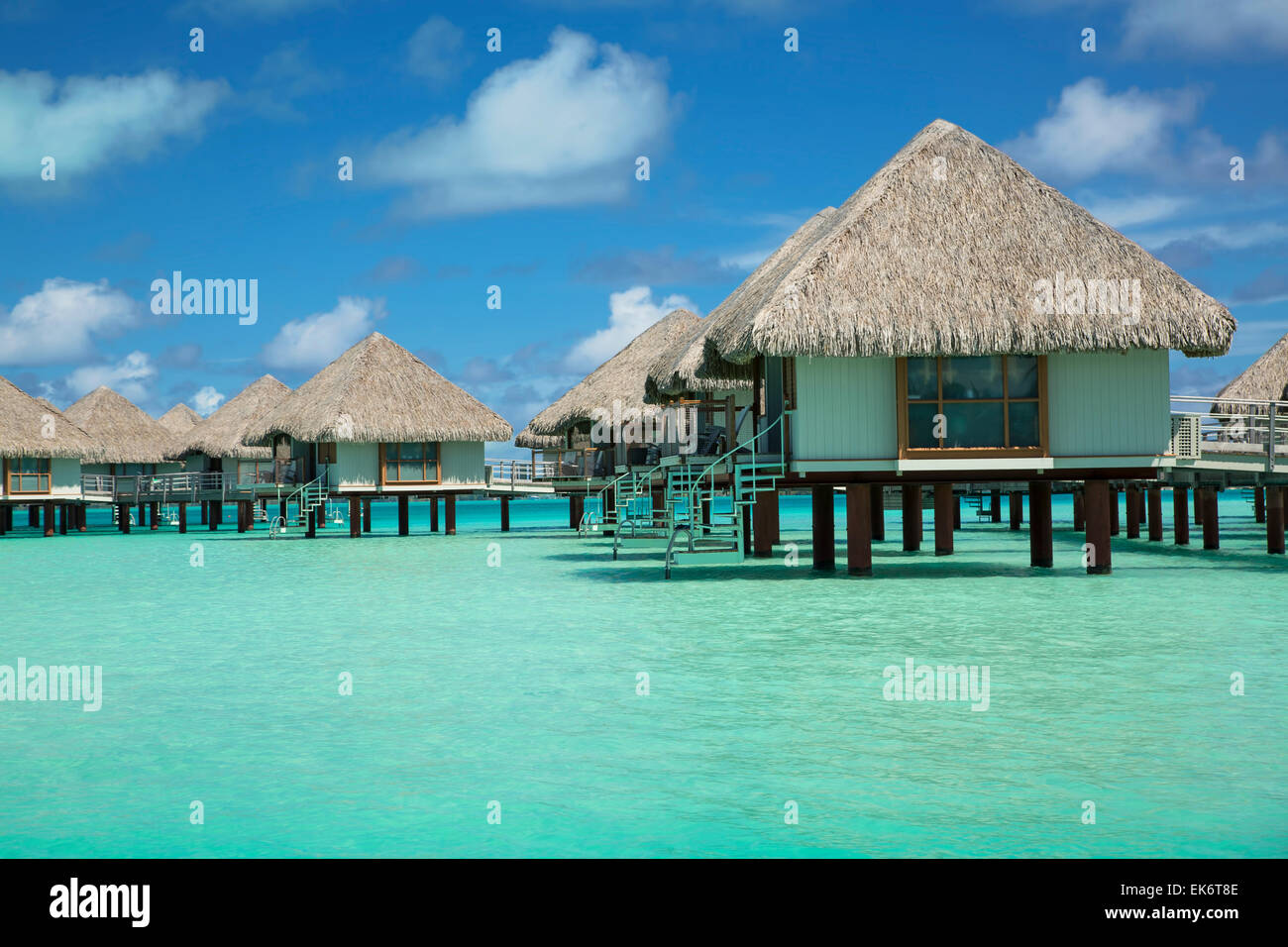 Huts at Bora Bora over turquoise waters and blue sky Stock Photo - Alamy