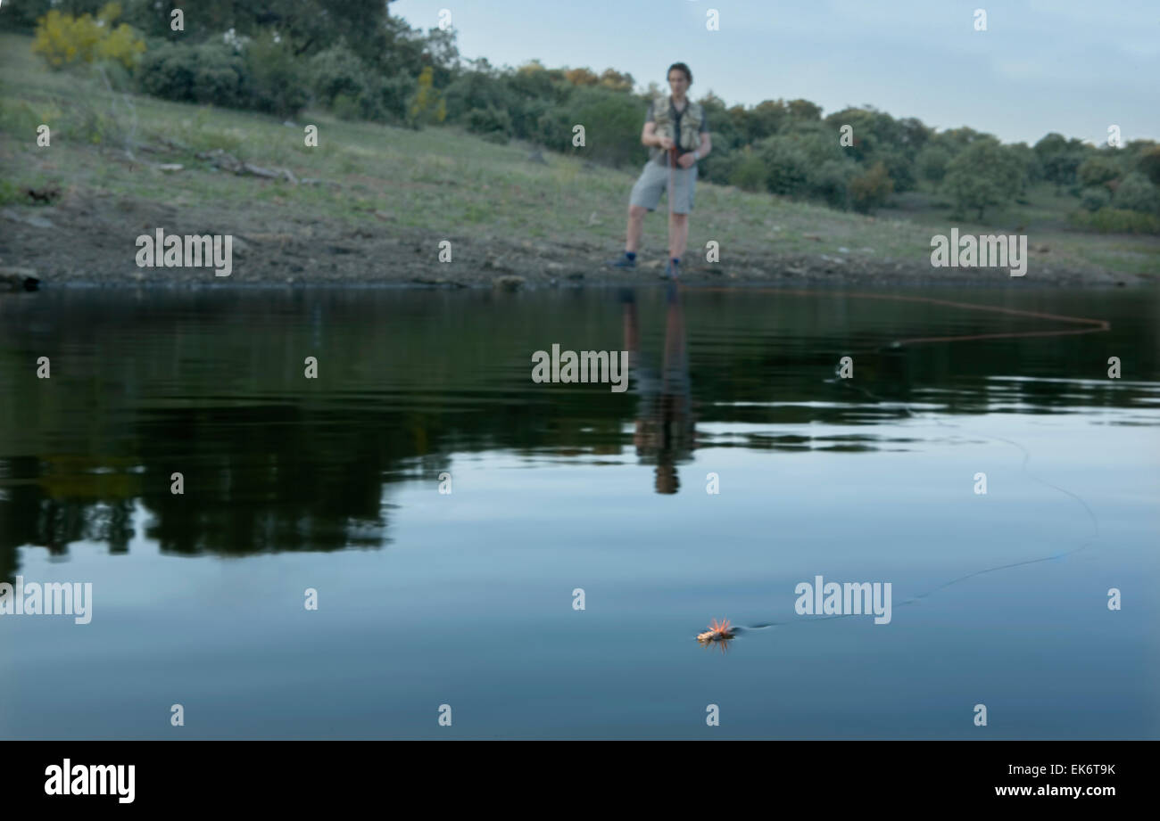 Fishing fly floats over the surface of the water in the foreground ...