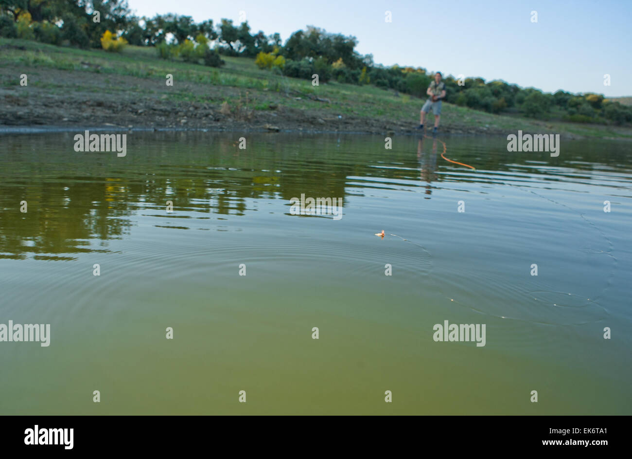Fishing fly floats over the surface of the water in the foreground ...