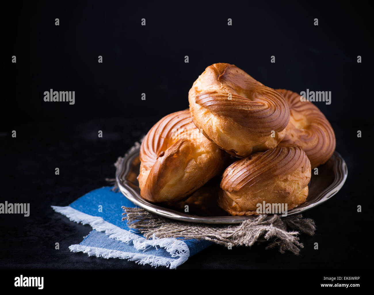 Choux pastry eclair ring with custard cream on dark background ...
