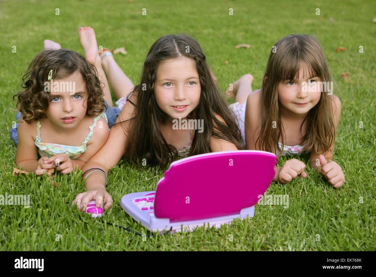 Three little girl playing with toy computer in grass Stock Photo - Alamy