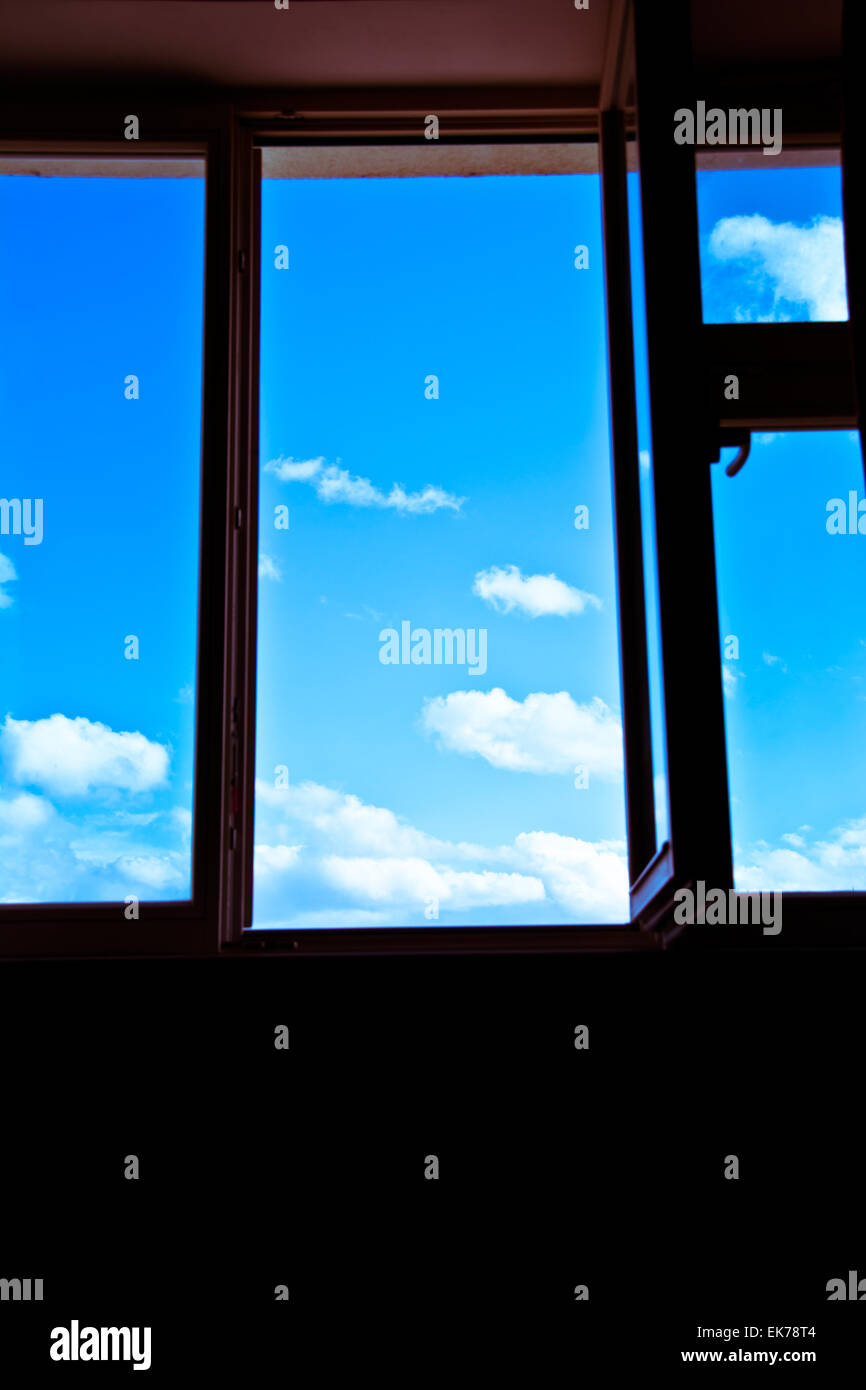 silhouette of an open window with blue sky and white clouds outside ...
