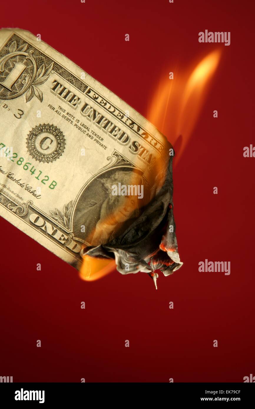 Dollar note burning in fire over red Stock Photo - Alamy
