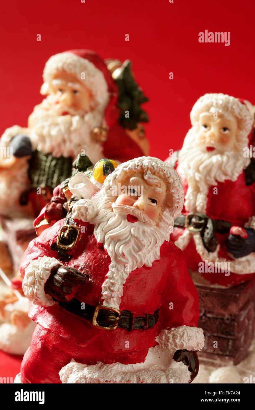 Three Santa Claus figurines over red background, studio Stock Photo - Alamy