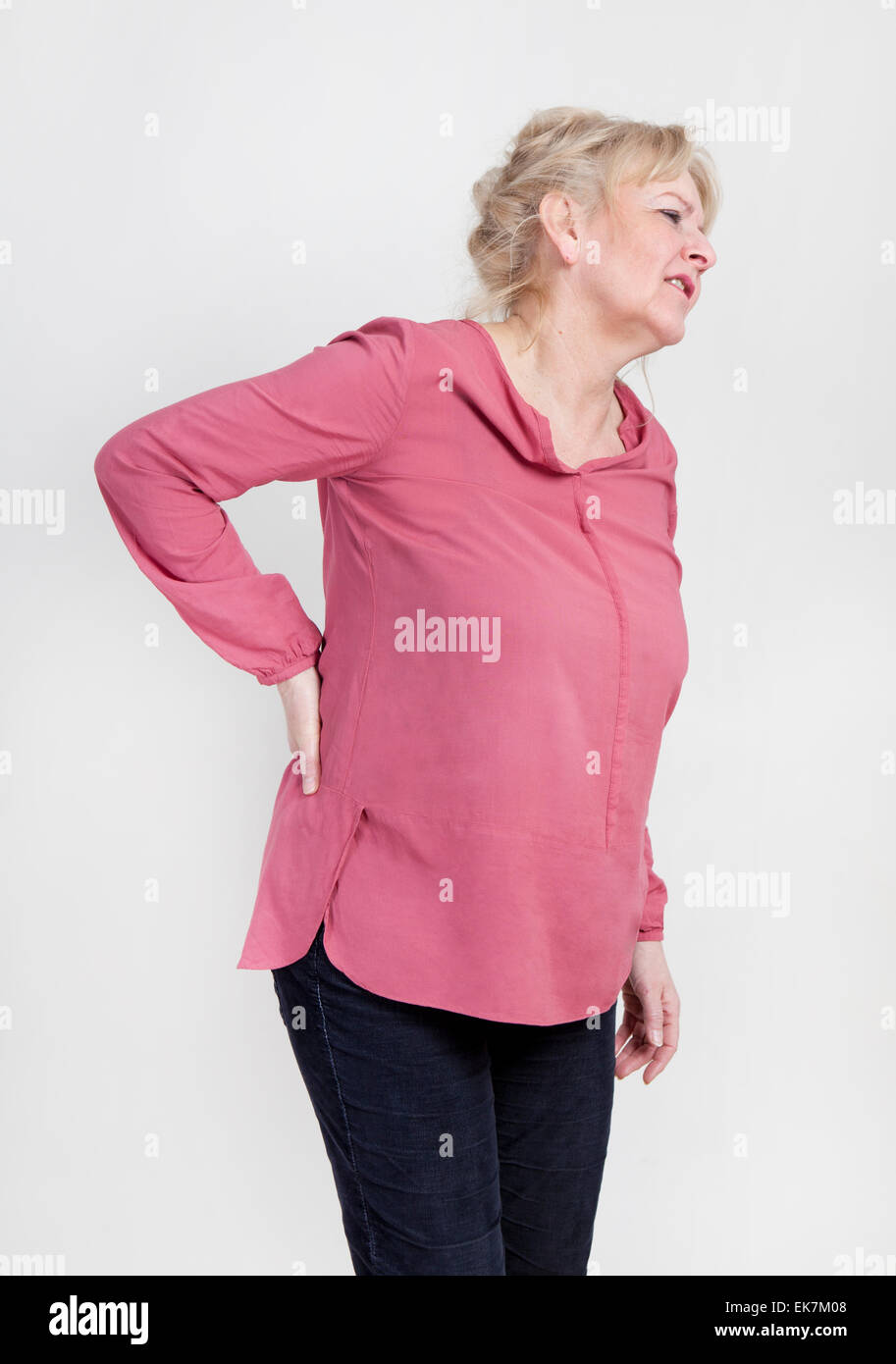 an older woman has pain and holds the back Stock Photo - Alamy