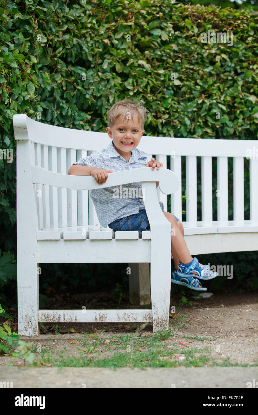 little boy sits on a bench in a park Stock Photo - Alamy