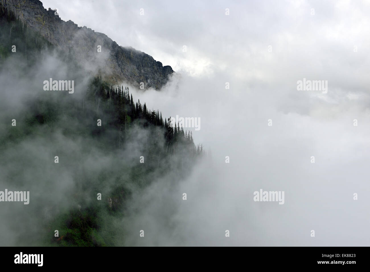 high and steep mountains surrounded by heavy clouds in Glacier National ...