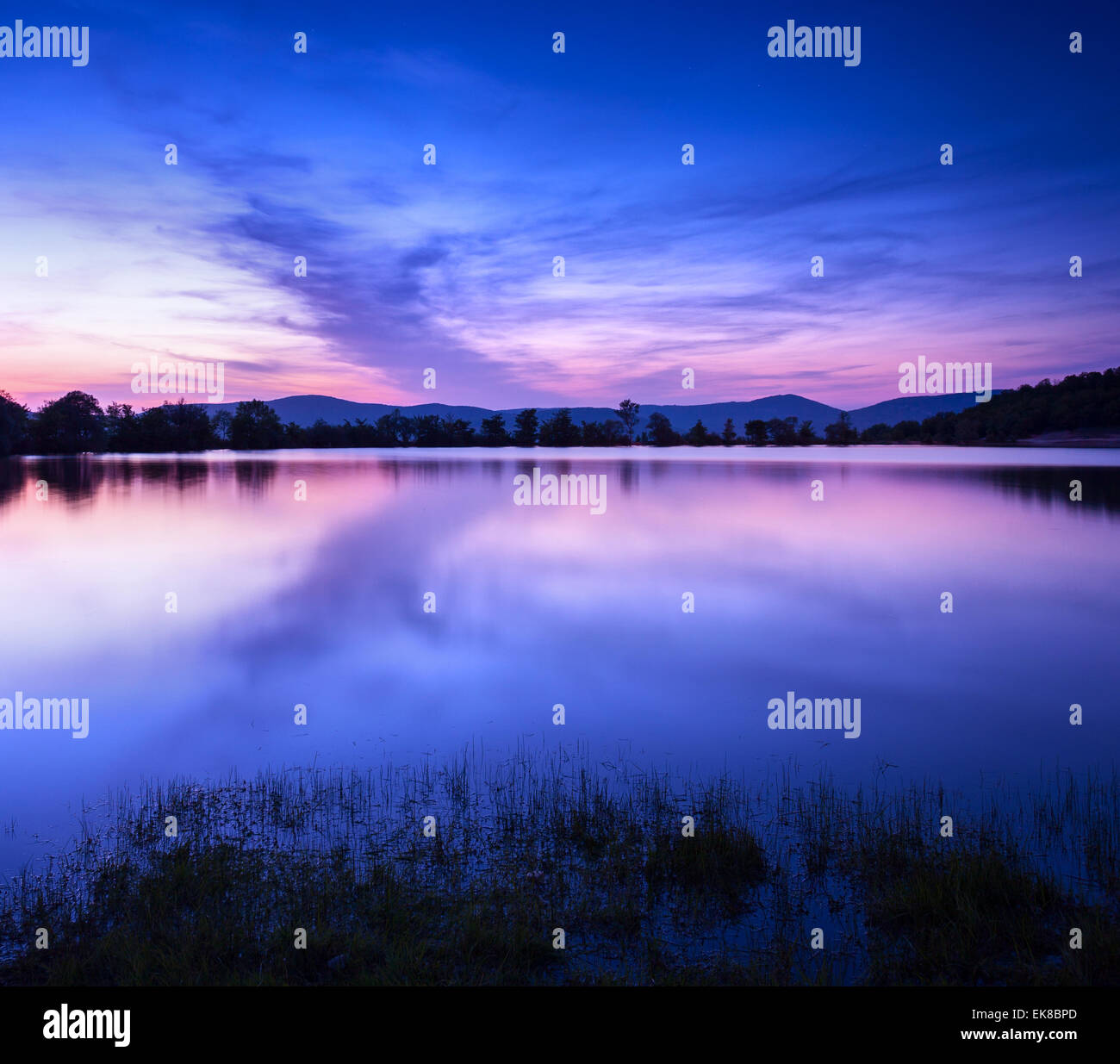 Beautiful spring night on the pond with stars, clouds and reflection in ...