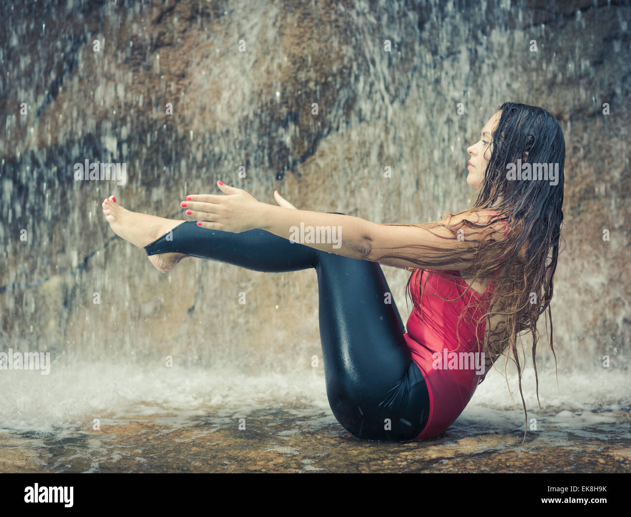 Woman practicing yoga near waterfall. Boat Pose. Navasana Stock Photo ...