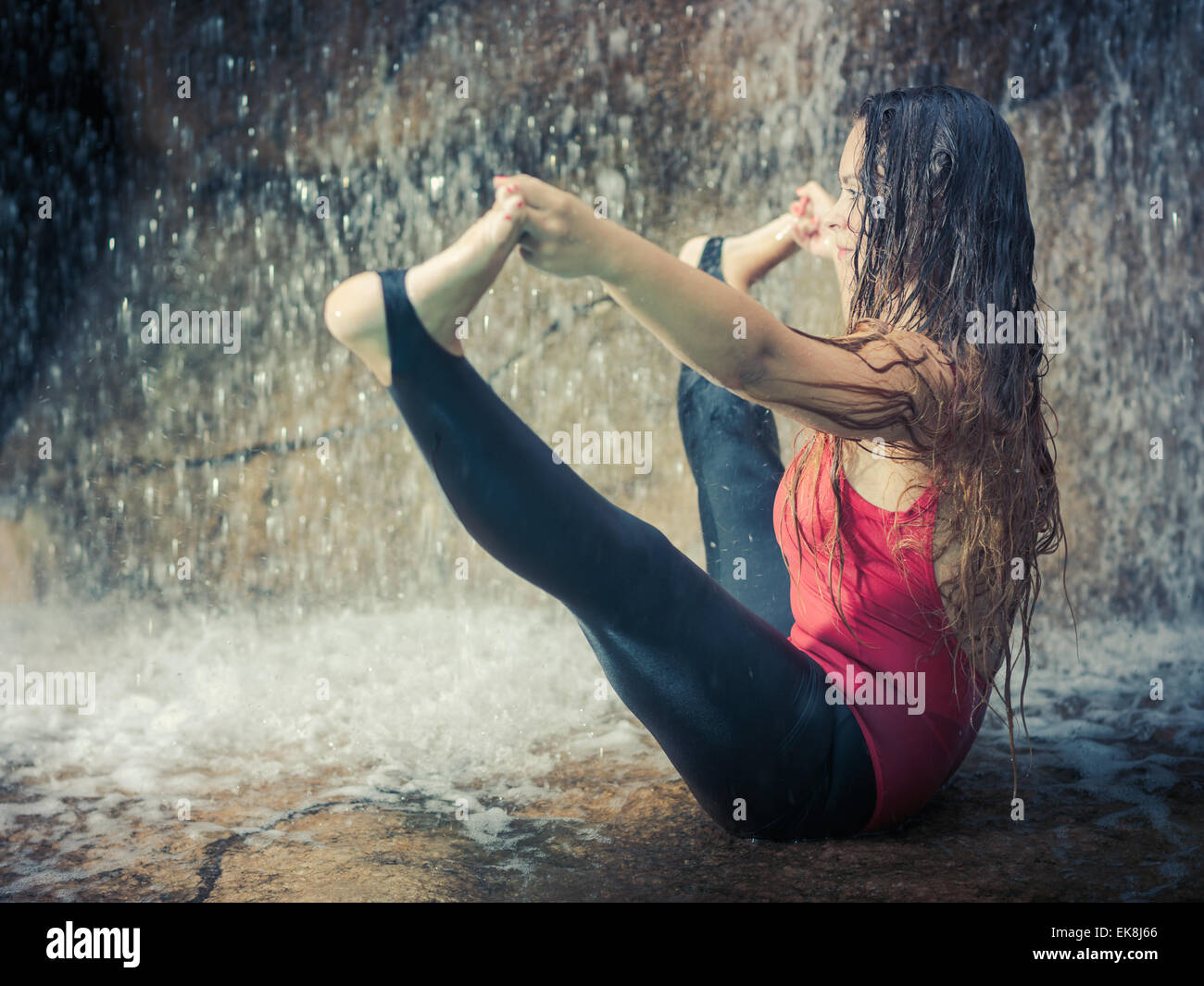 Woman practicing yoga near waterfall. Boat Pose. Navasana Stock Photo ...