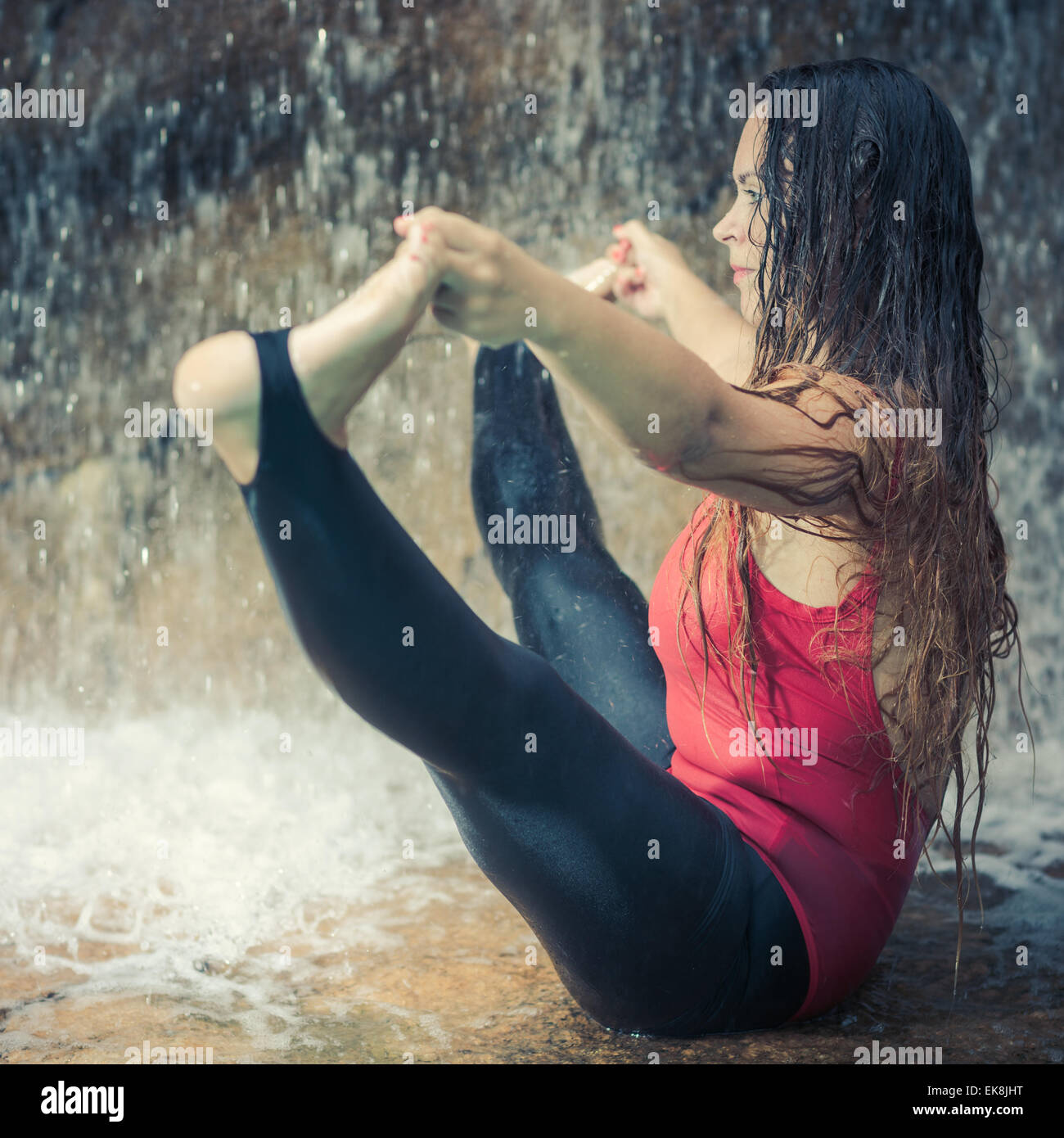 Woman practicing yoga near waterfall. Boat Pose. Navasana Stock Photo ...