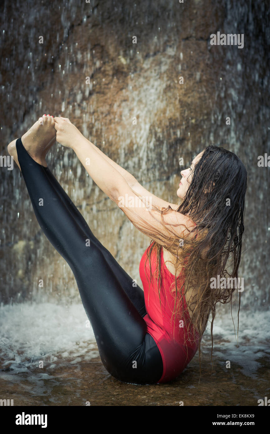 Woman practicing yoga near waterfall. Boat Pose. Navasana Stock Photo ...