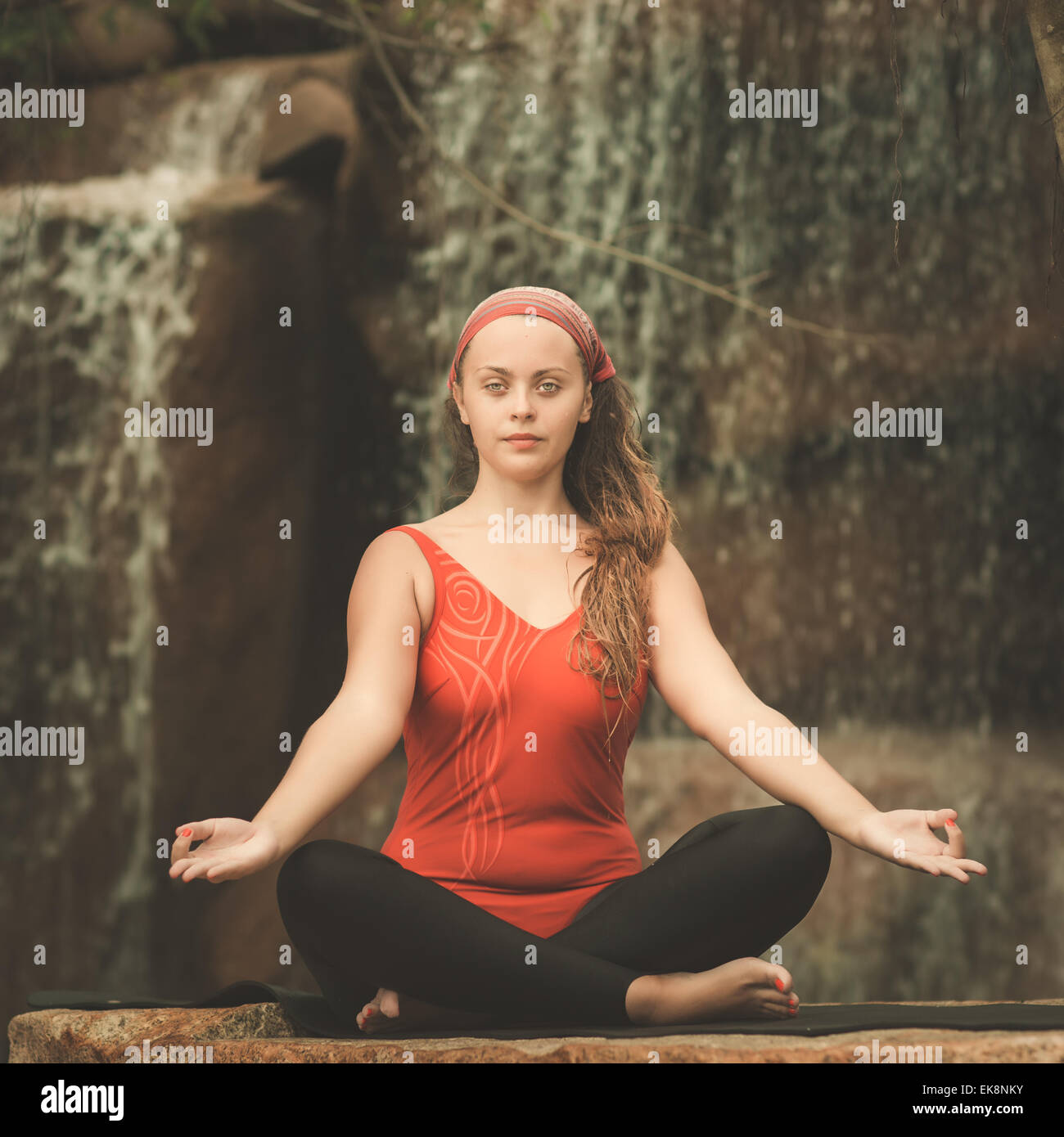 Woman practicing yoga near waterfall. Easy Pose. Sukhasana.Toned Stock ...