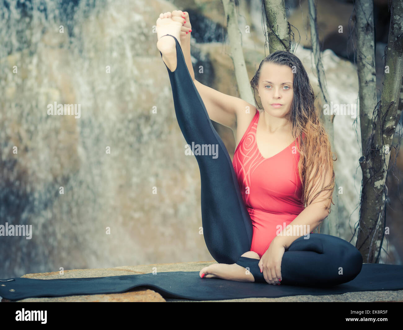 Young woman is practicing yoga near waterfall Stock Photo - Alamy