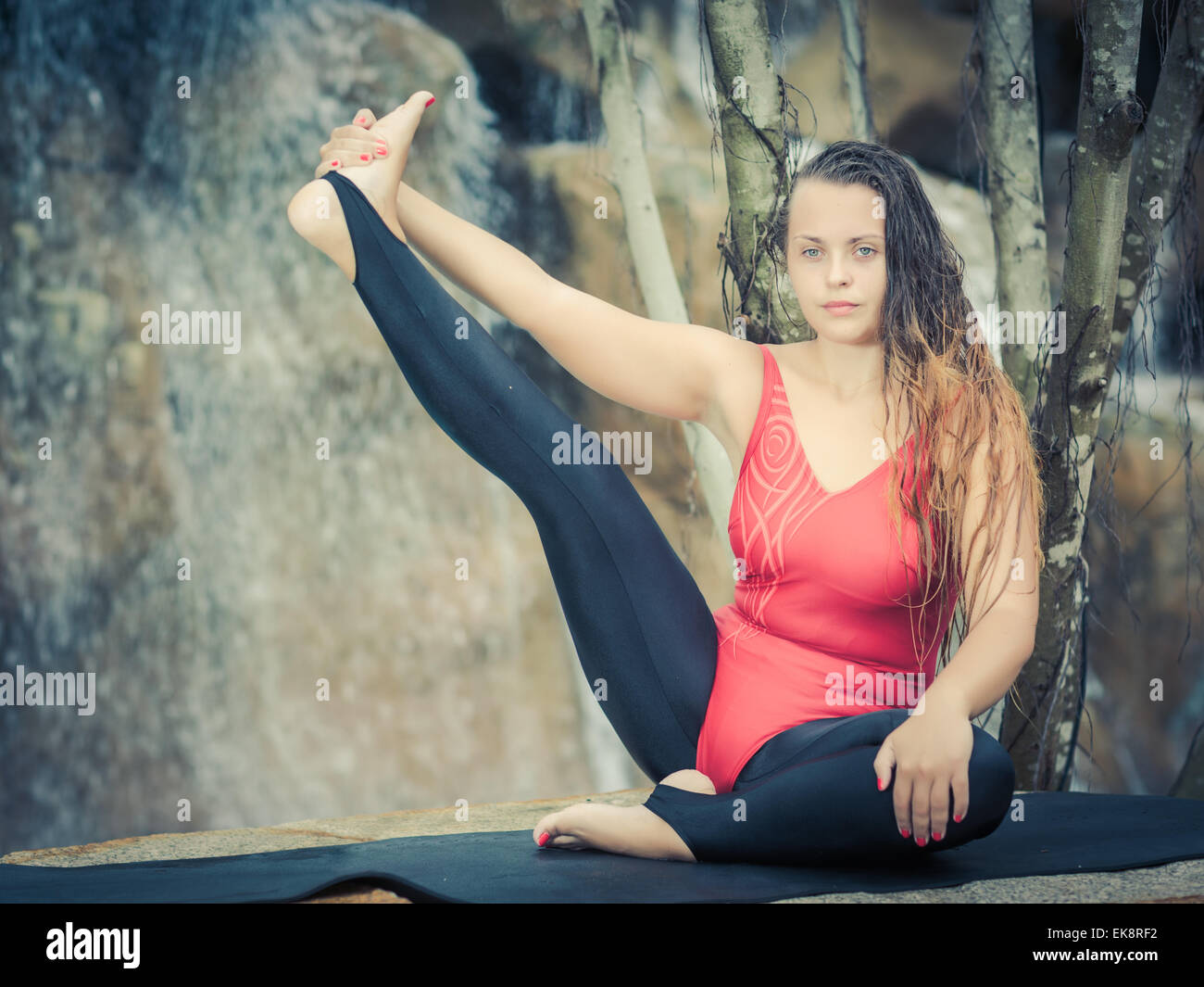 Young woman is practicing yoga near waterfall Stock Photo - Alamy