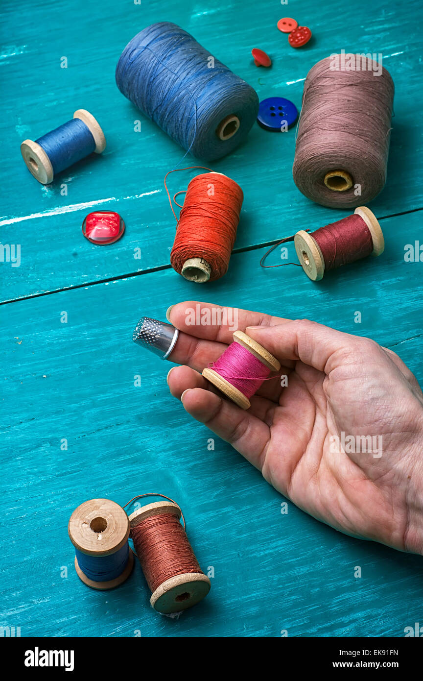 human hand and thread with buttons on turquoise wooden background Stock ...