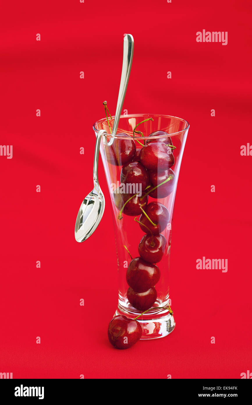 glass of cherry and spoon on a red background Stock Photo - Alamy