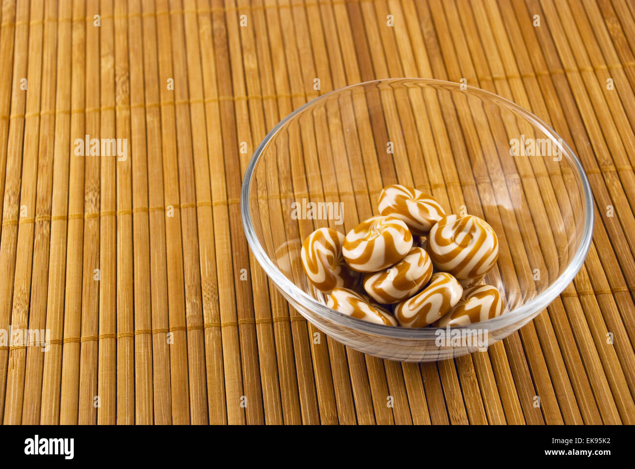Candy in a glass bowl on a bamboo mat Stock Photo - Alamy