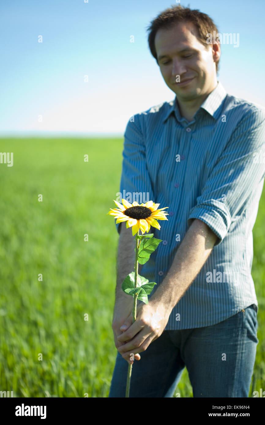 young man standing with a sunflower in the green field Stock Photo - Alamy