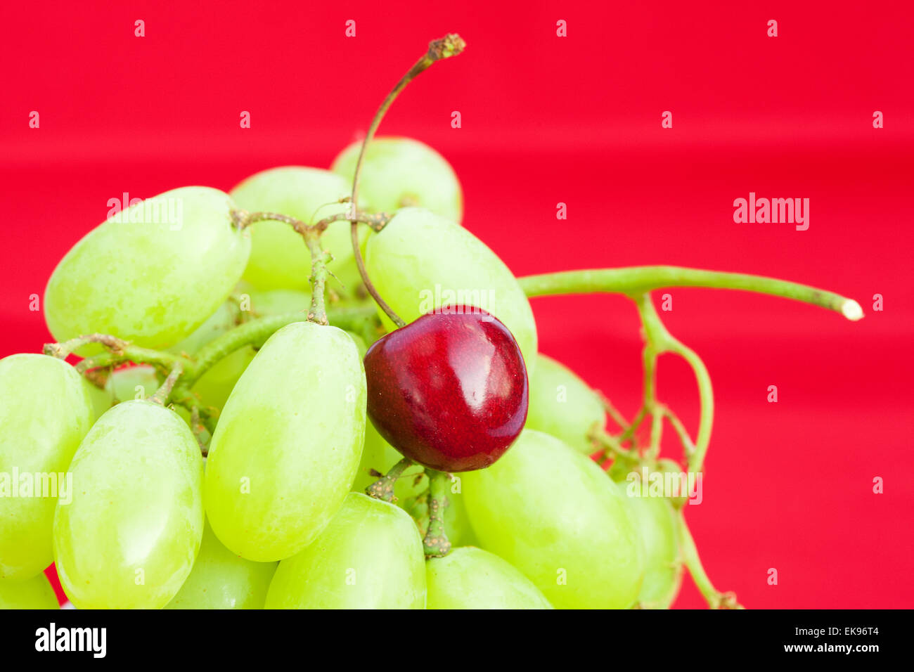 Grapes and cherry on a red background Stock Photo - Alamy