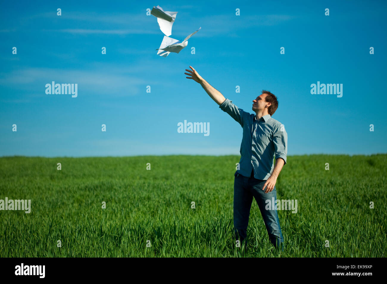 young man throwing a paper in the green field Stock Photo - Alamy
