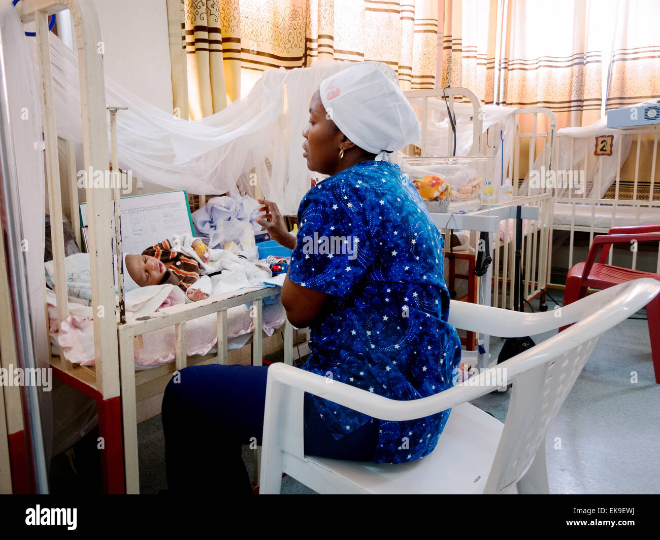 An African nurse nursing a baby in a ward; The Heal Africa charity ...